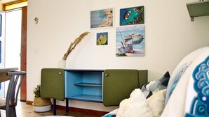 Um quarto com uma cama, um armário verde, uma parede com obras de arte e uma janela.