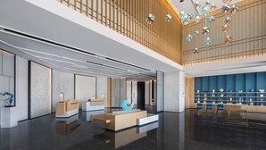 Um hall moderno com balcão de recepção, área de estar e luminárias decorativas no teto.