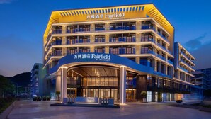 Um hotel de vários andares com design moderno, com varandas em cada pavimento e uma entrada imponente.
