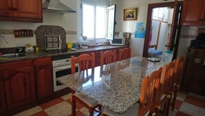 Uma cozinha com bancadas de granito, armários de madeira, um fogão e uma área de jantar com cadeiras.