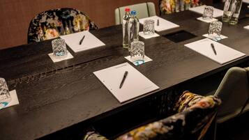 Uma mesa de conferência com garrafas de água, copos e cadernos.