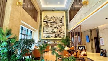 Um hall amplo com um grande mural, áreas de estar e plantas internas.