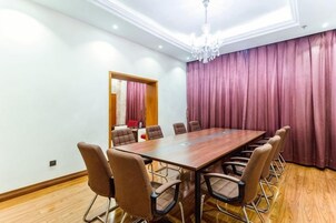 Uma sala de conferência com uma mesa comprida, cadeiras e um lustre.