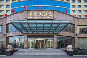 Entrada do Hotel Huasheng com uma cobertura de vidro, uma entrada central e duas estátuas de cada lado.
