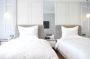 Quarto de hotel com duas camas, uma escrivaninha e uma televisão.