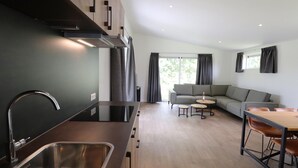 Uma cozinha moderna com forno embutido, pia de aço inoxidável e área de refeições com mesa e cadeiras de madeira.