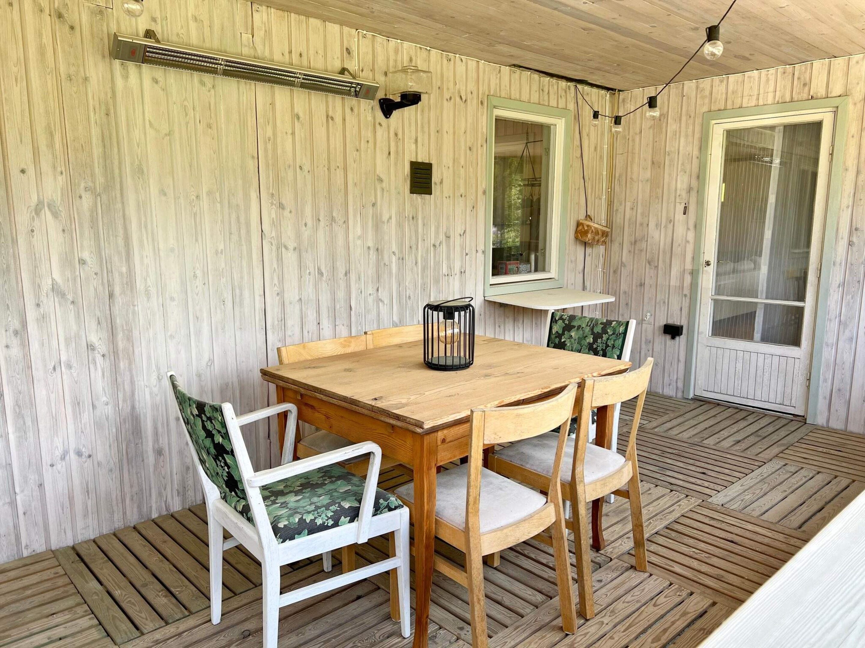 Interior de madeira com uma mesa, cadeiras, uma janela e uma porta.