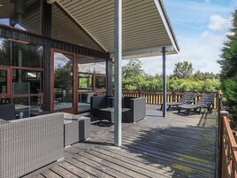 Um deck coberto ao ar livre com móveis de vime e piso de madeira.