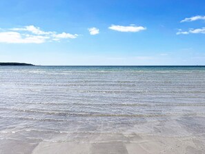 Uma praia com águas cristalinas e uma terra firme ao longe.