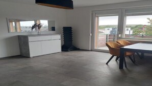 Cozinha moderna com bancada branca e eletrodoméstico preto. Há uma área de jantar com mesa e cadeiras.