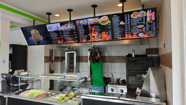 Uma área de buffet com diversas opções de comida e um painel digital de menu.