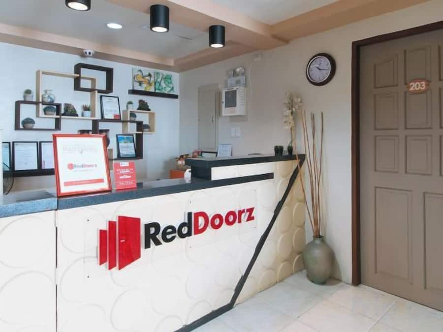 Balcão de recepção com o logotipo RedDoorz, um relógio e uma porta com o número 203.