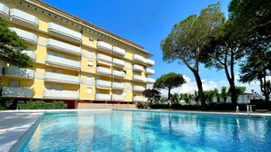 Hotel com piscina, várias varandas e árvores ao redor.