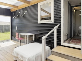 Quarto com uma cama, uma mesinha, uma cadeira, um espelho e uma escada que dá para um banheiro.