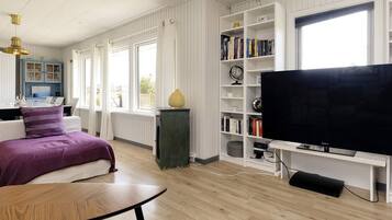Quarto com cama, mesa, estante, televisão e janela.