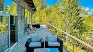 Um terraço moderno ao ar livre com móveis de vime e uma sala envidraçada.