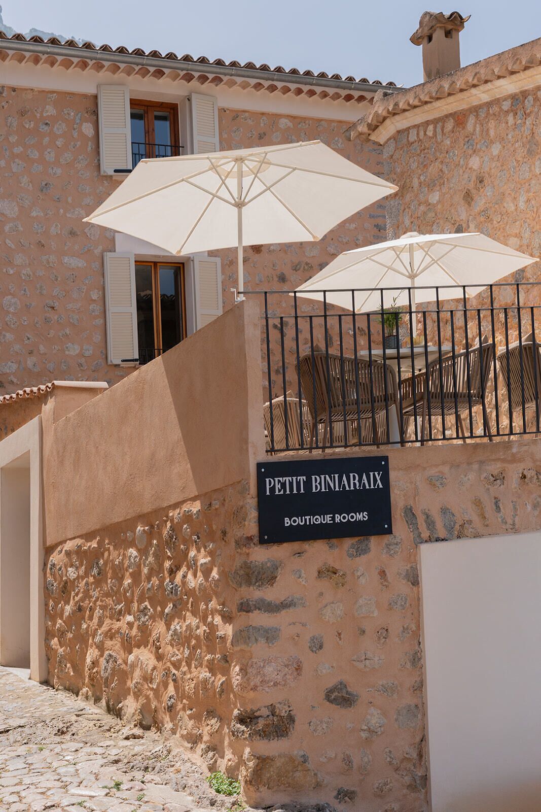 Um edifício de pedra com uma placa que diz 'PETIT BINIAIX BOUTIQUE ROOMS'.