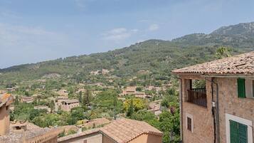 Terraço com mobiliário de exterior e vista para uma aldeia no topo da colina.