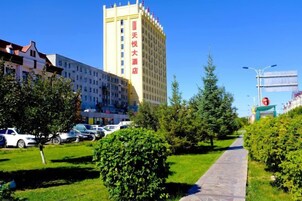 Um hotel com um pátio central, rodeado por vegetação e carros estacionados.