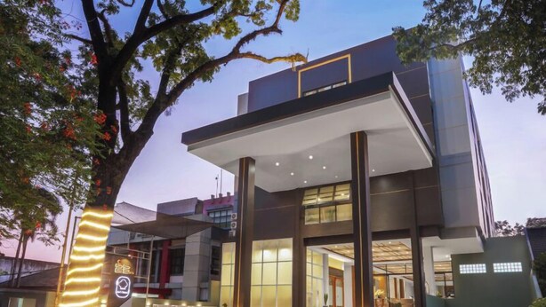 Um edifício moderno com telhado plano, janelas amplas e área de entrada coberta.