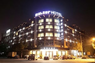Hotel com fachada curva, vários andares e letreiros iluminados.