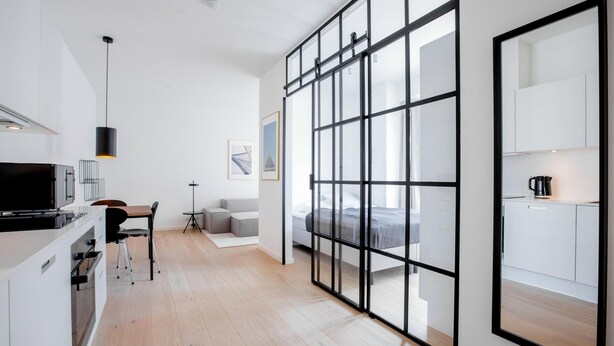 Quarto de hotel moderno com cozinha, mesa de jantar e uma grande janela com vista.