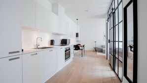 Uma cozinha moderna com armários brancos, piso de madeira e um espaço de refeições com mesa e cadeiras.