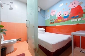 Quarto de hotel com cama, chuveiro, vaso sanitário e um mural na parede.