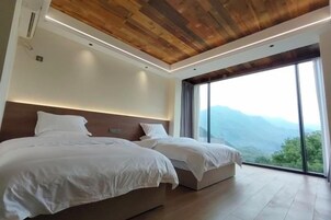 Quarto com duas camas, teto de madeira e uma janela ampla com vista para a montanha.