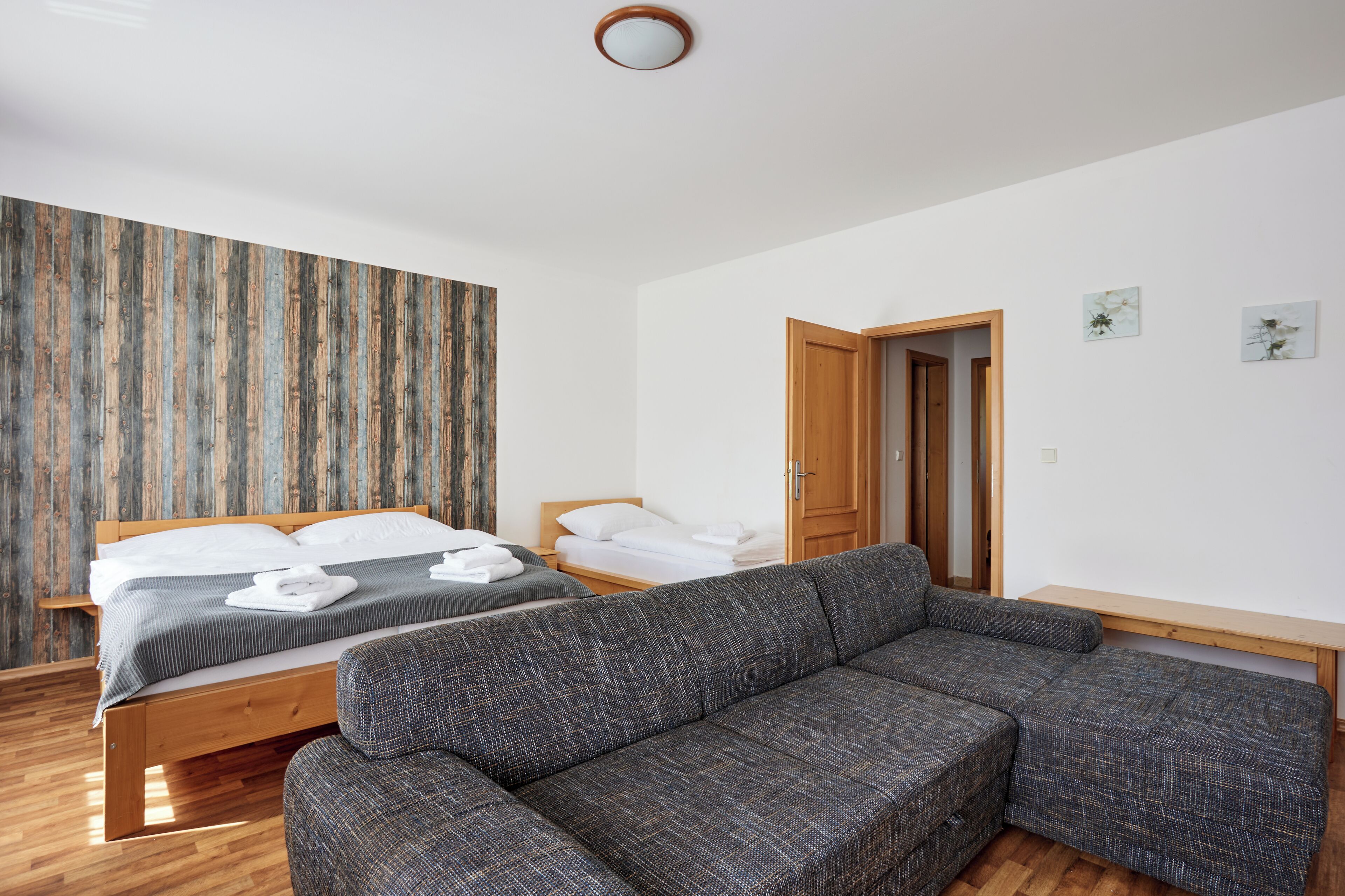 Quarto com cama, sofá e piso de madeira.