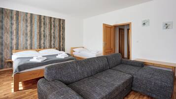 Quarto com cama, sofá e piso de madeira.