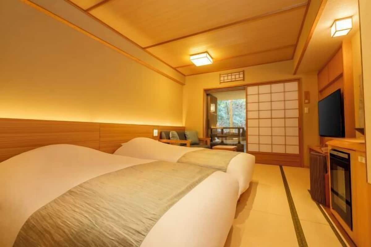Um quarto tradicional em estilo japonês, com piso de tatame, teto de madeira baixo e uma porta deslizante para uma varanda.