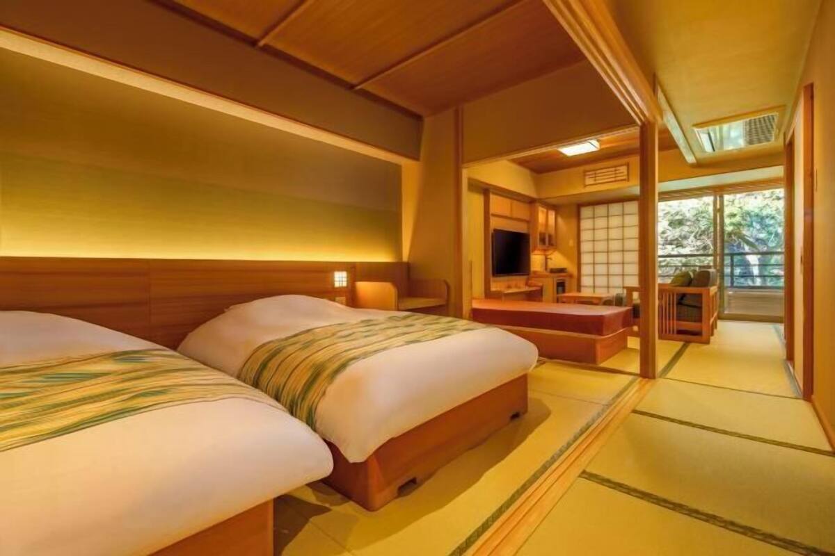 Um quarto em estilo japonês tradicional, com tatames, uma cama de madeira baixa e portas deslizantes que dão para a vista.