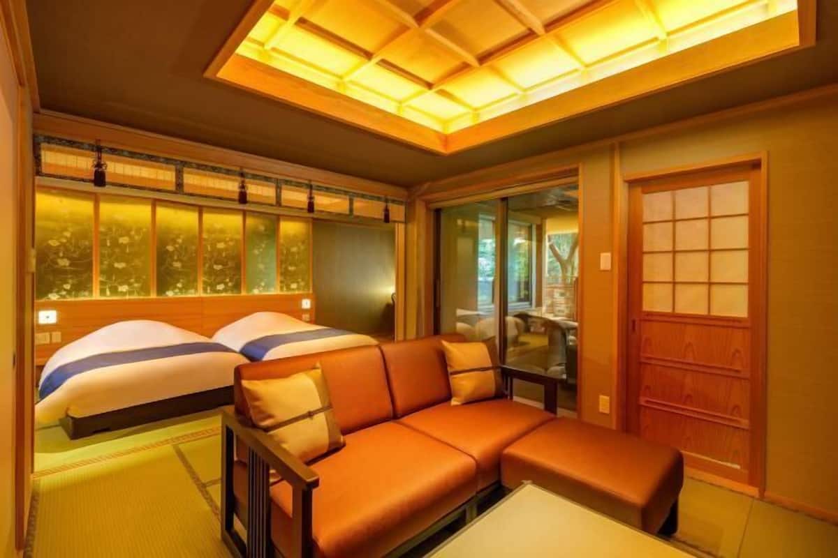 Um quarto japonês tradicional com piso de tatame, mesa baixa, sofá e duas camas com roupa de cama azul.