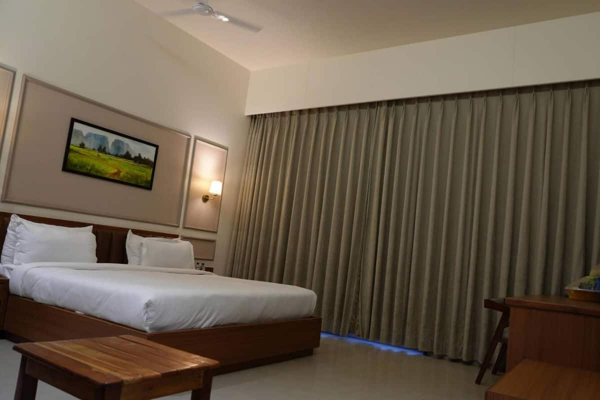 Quarto de hotel com uma cama grande, uma mesa, uma cadeira, uma televisão e um quadro na parede.