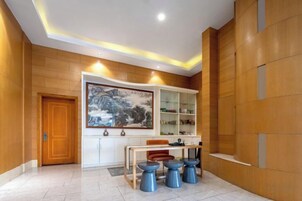 Um interior moderno com parede de madeira, uma grande obra de arte emoldurada, área de refeições com banquetas e um armário branco com prateleiras.