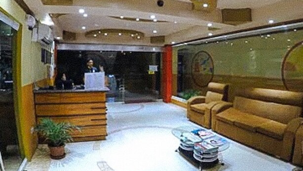 Um hall de entrada com uma mesa de recepção, um sofá, uma mesa de centro e um vaso de planta.
