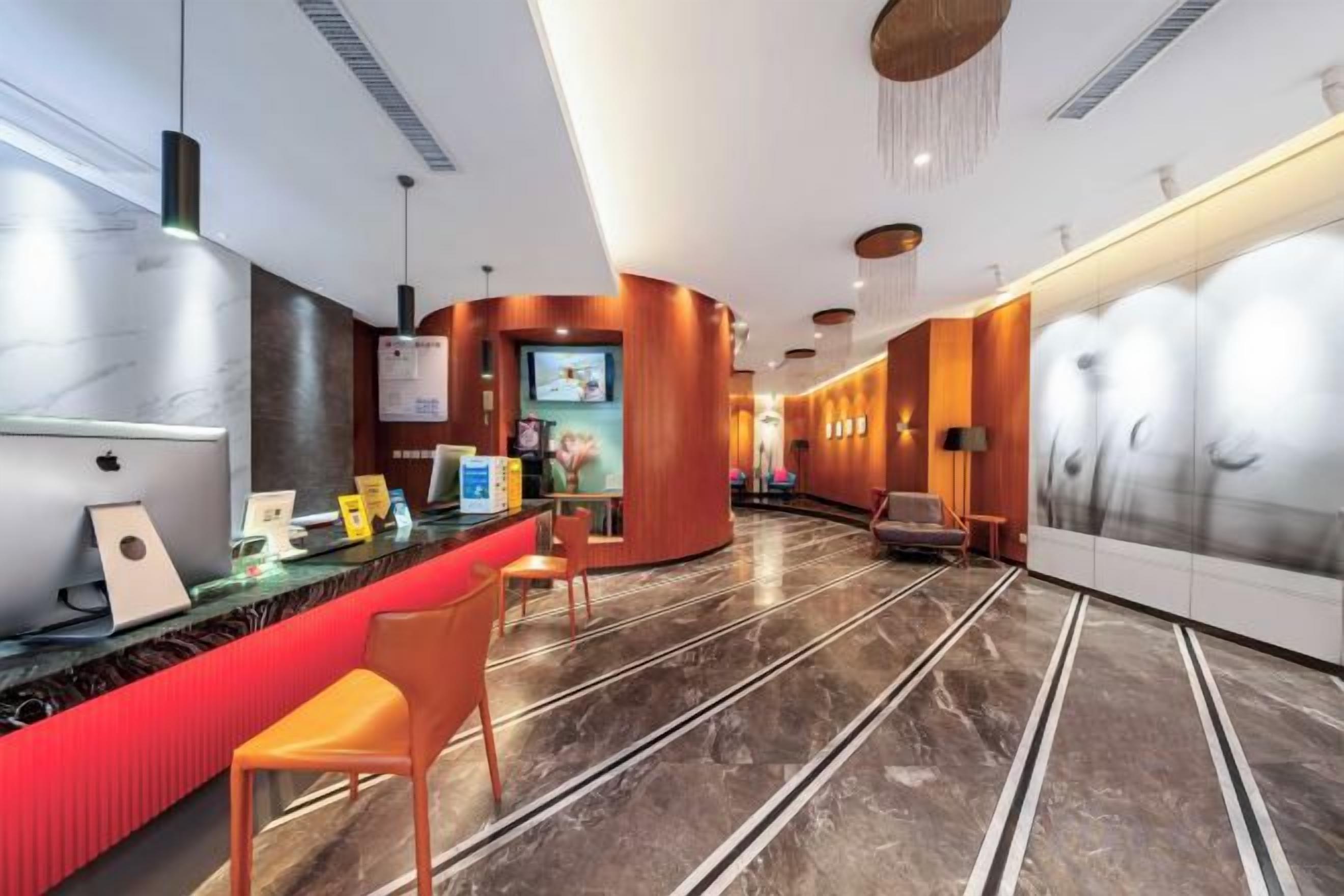 Um hall de hotel com balcão de recepção, área de estar e uma parede grande com um mural.