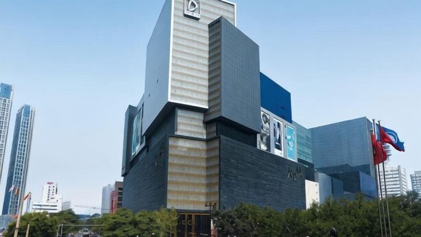 Um edifício moderno com uma seção vertical marcante e um grande painel digital.