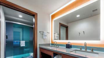 Casa de banho moderna com chuveiro em cabine de vidro, um espelho grande e duas pias com torneiras.