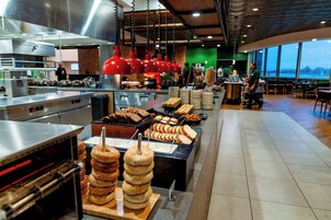 Buffet com diversos alimentos e cozinha ao fundo.