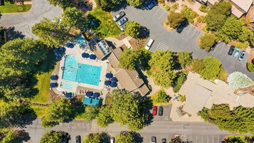 Vista aérea de um empreendimento com piscina, áreas de estacionamento e vegetação ao redor.