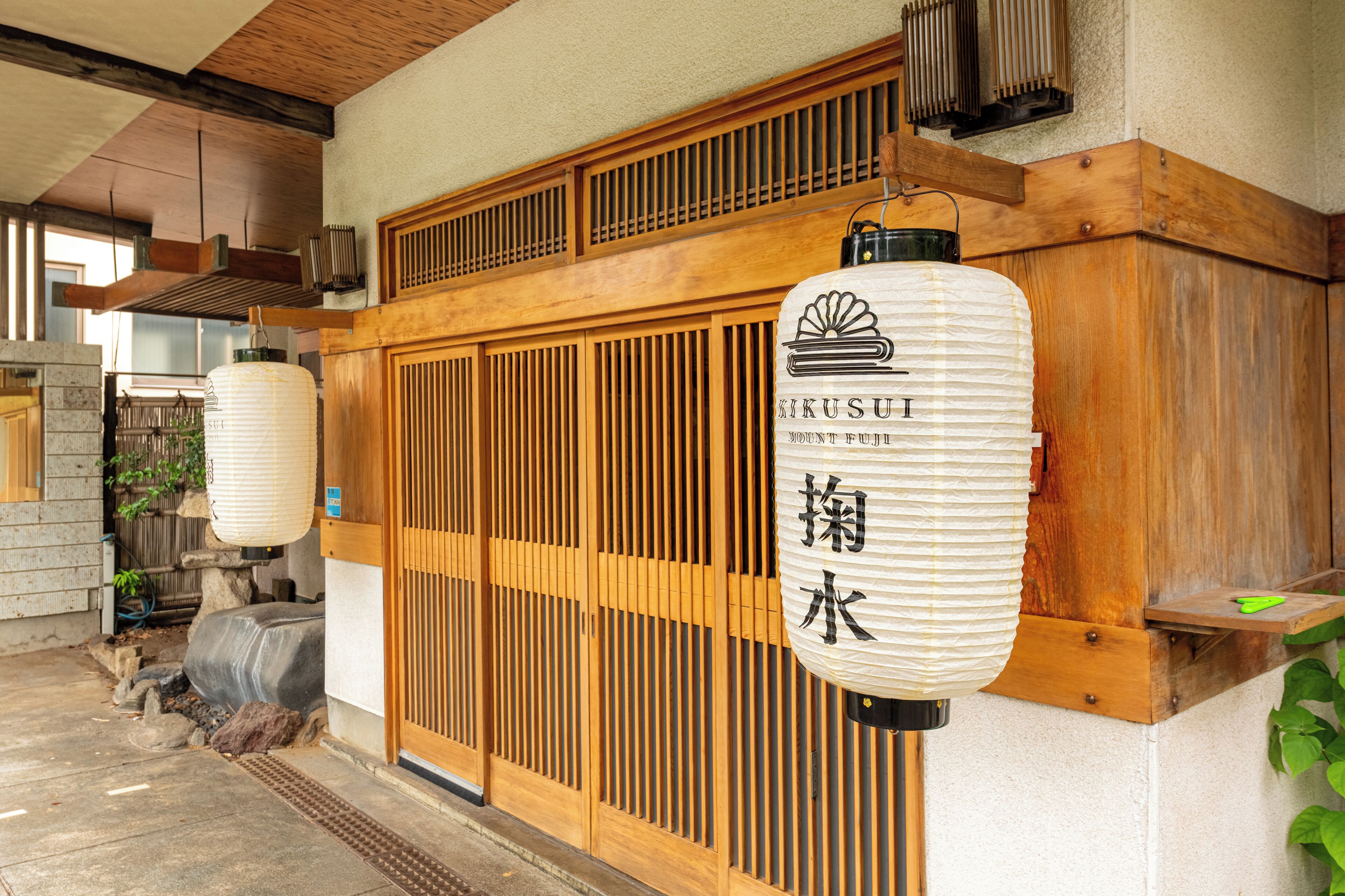 Um edifício tradicional japonês, com portas de correr de madeira e um candeeiro com caracteres japoneses.