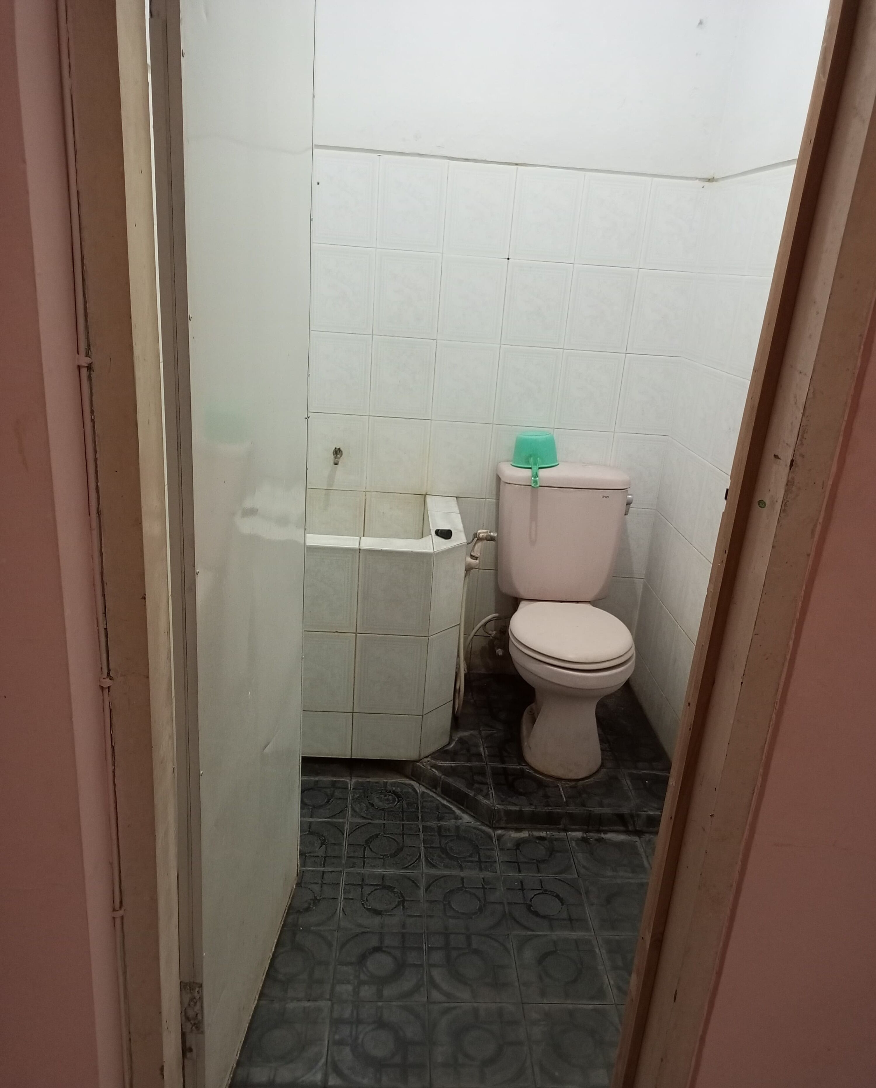 Casa de banho pequena e estreita, com sanita, lavatório e zona de duche.