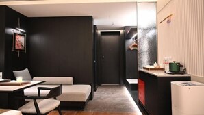 Quarto de hotel pequeno e funcional, com uma cama, uma mesinha, uma cadeira, cozinha compacta e closet espaçoso.