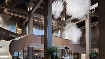 Um hall espaçoso com uma escadaria imponente, um elemento decorativo de água e um lustre moderno.