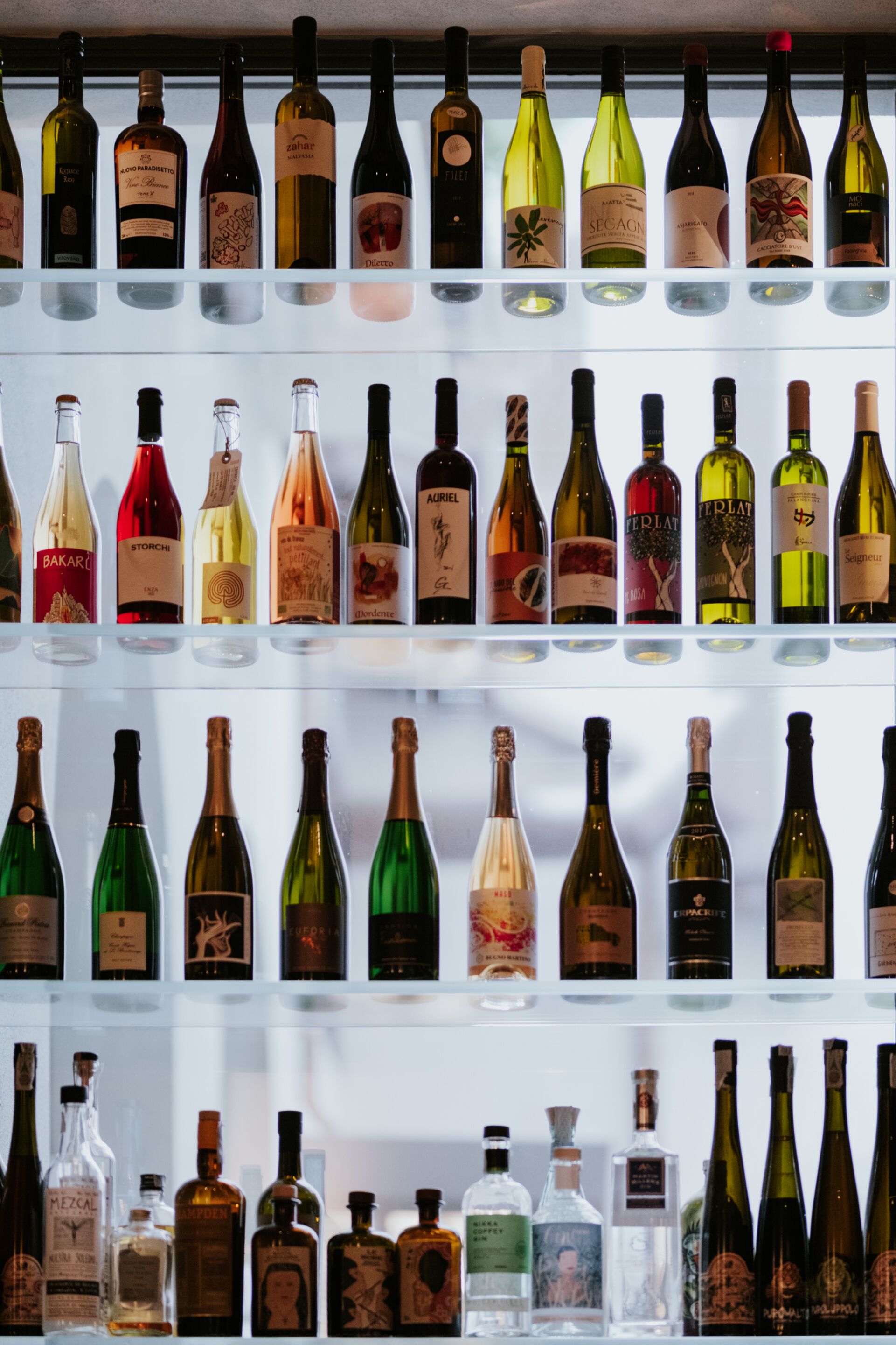 Uma estante com diversos vinhos.