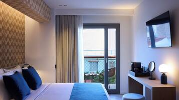 Quarto de hotel moderno com uma cama grande, uma escrivaninha com espelho e vista para o exterior.
