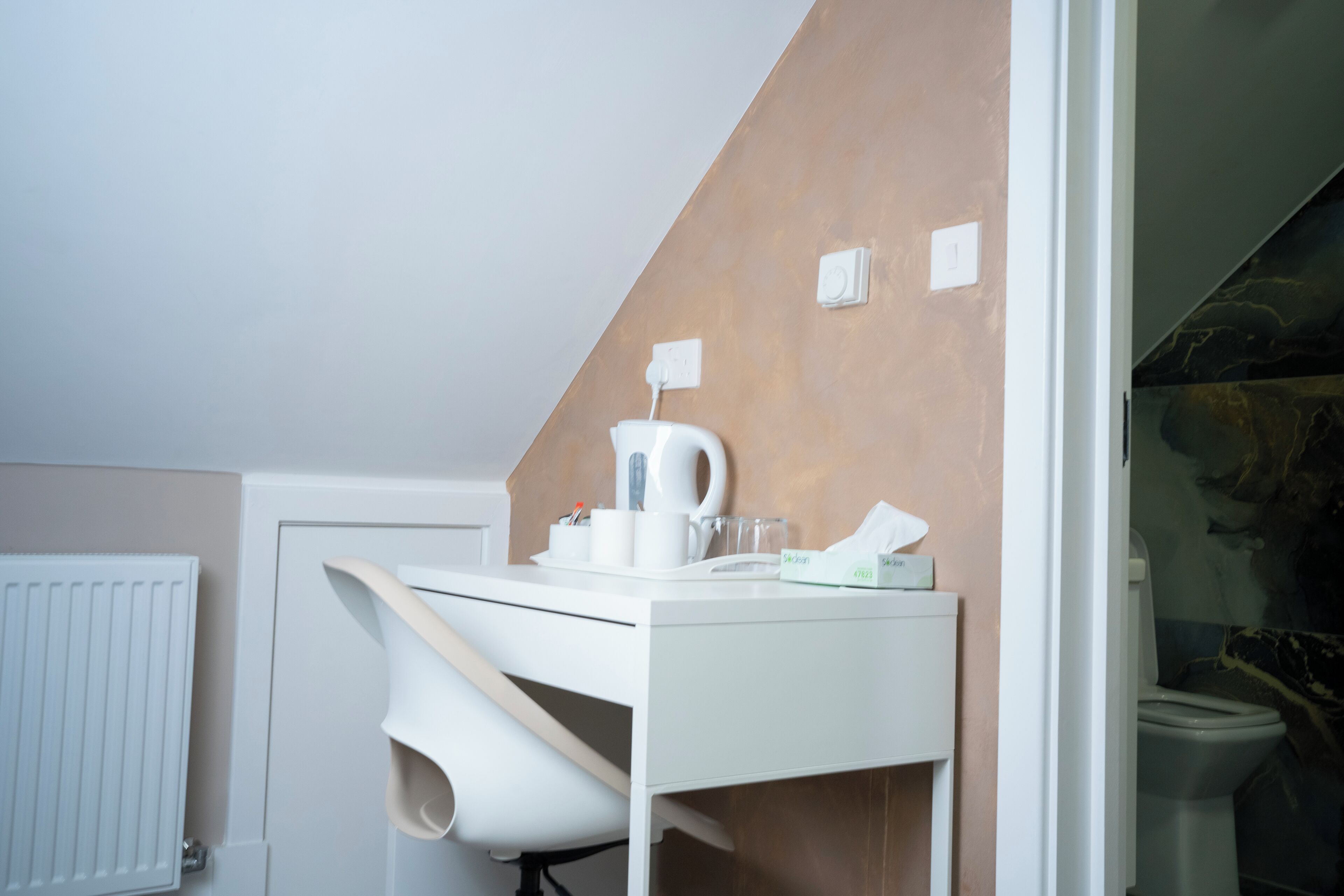 Um banheiro moderno com toucador branco, porta-toalhas, vaso sanitário e área de chuveiro.