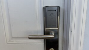 Uma fechadura digital de quarto de hotel em uma porta branca.